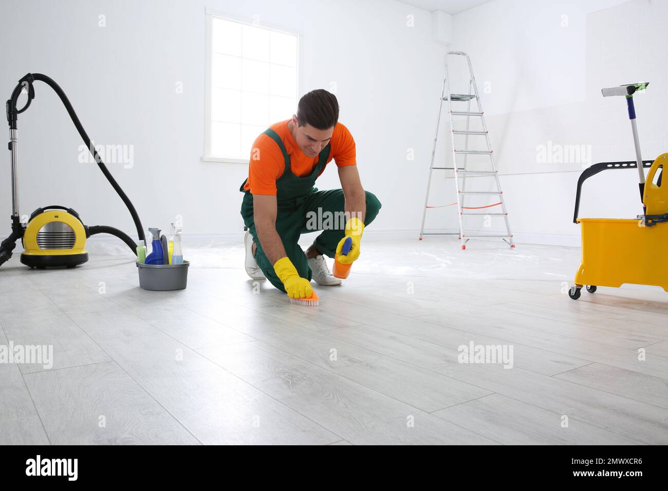 Professional janitor cleaning floor with brush and detergent after ...