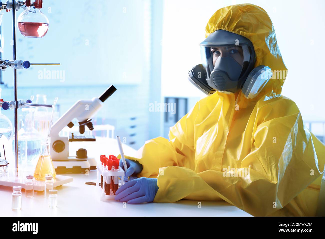Scientist in chemical protective suit working with blood samples at ...