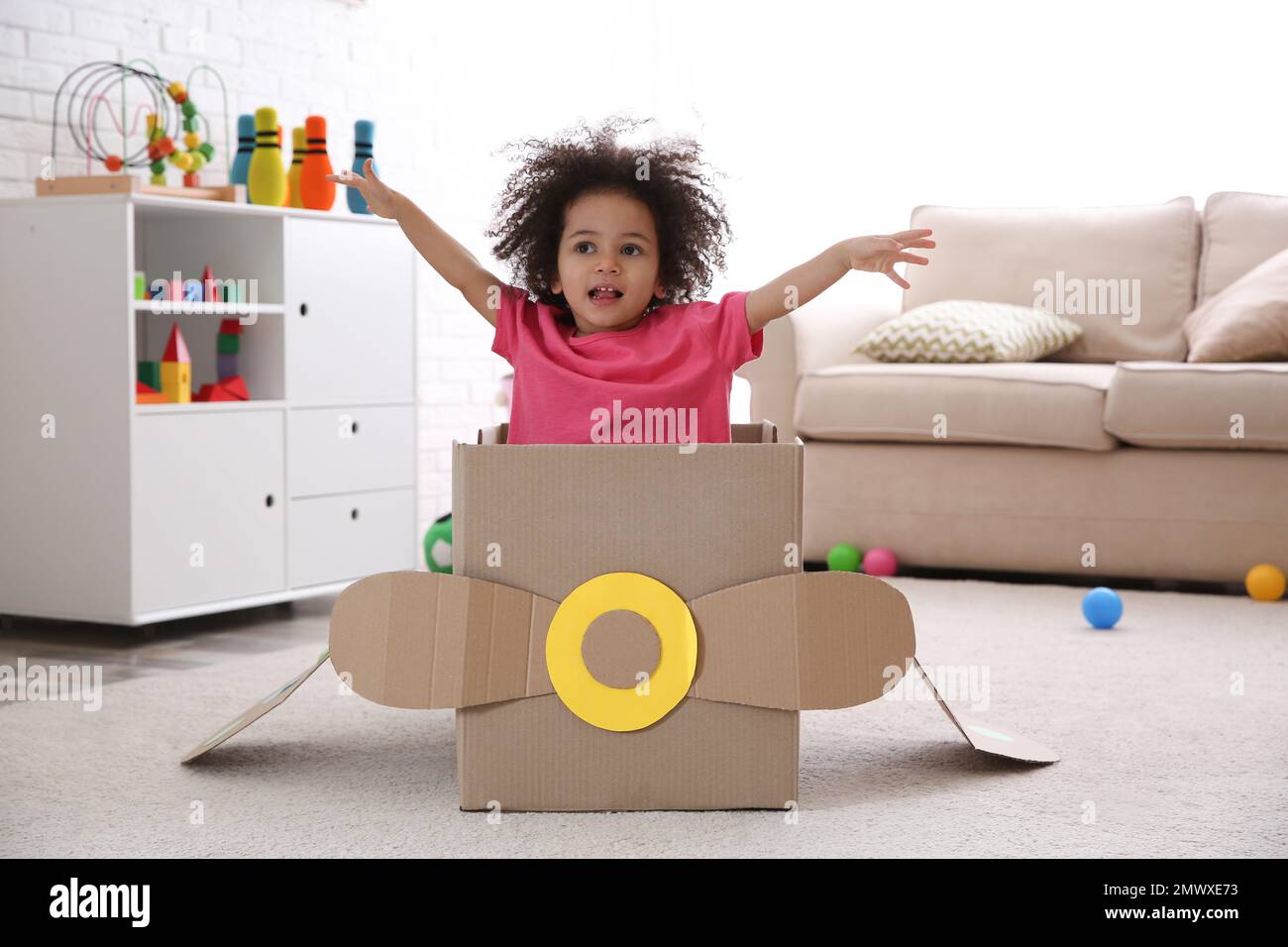 Cute African American child playing with cardboard plane at home Stock ...