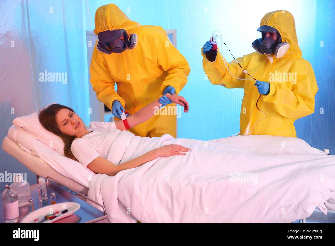 Paramedics wearing protective suits examining patient with virus in ...