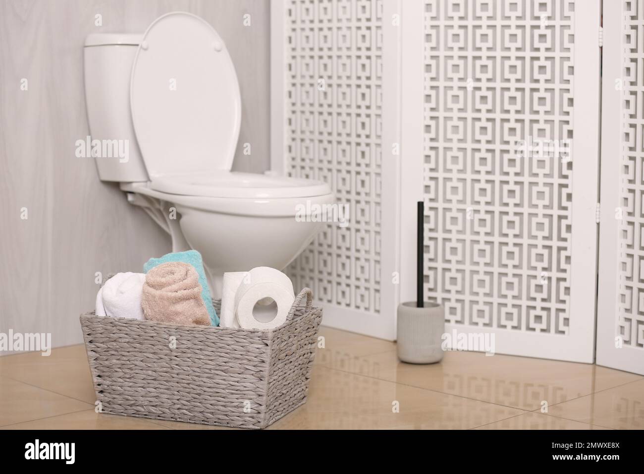 White toilet bowl near folding screen in bathroom Stock Photo - Alamy