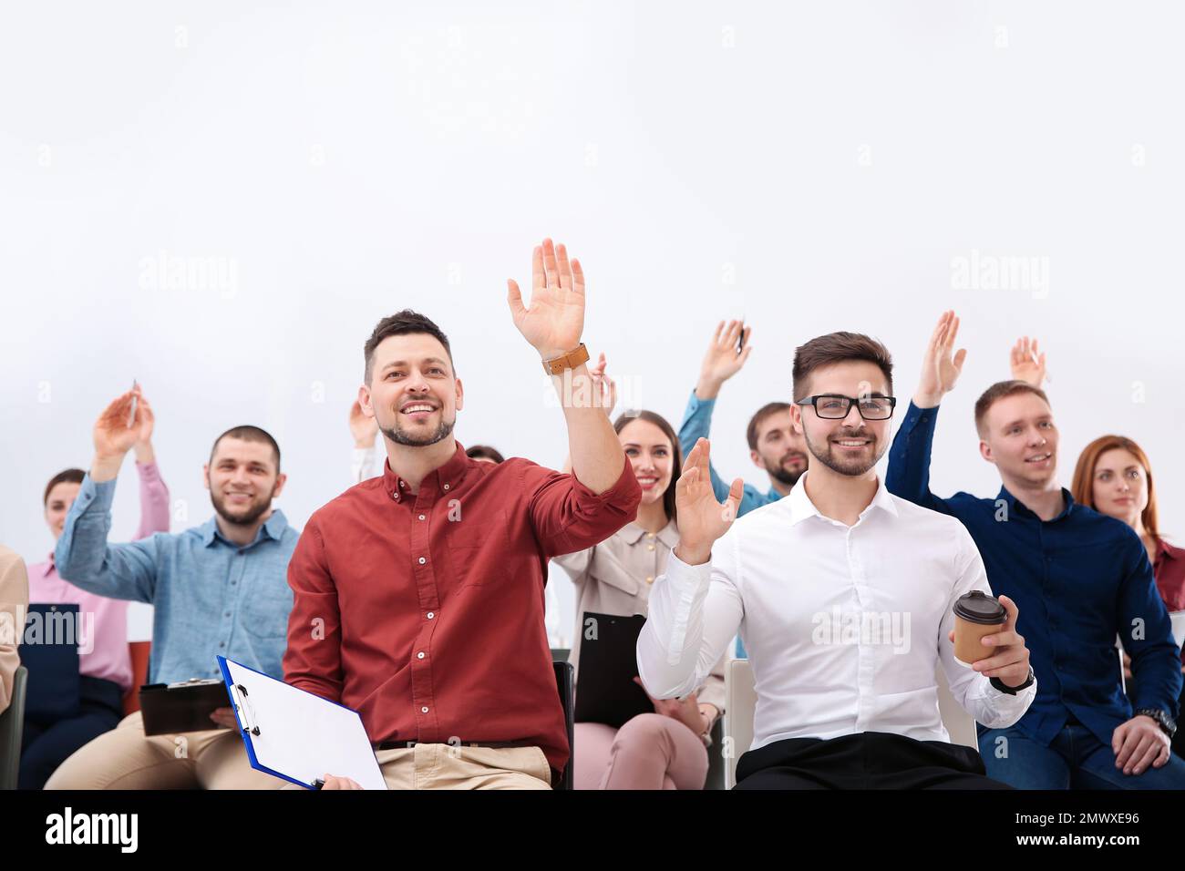 People raising hands to ask questions at business training on white ...