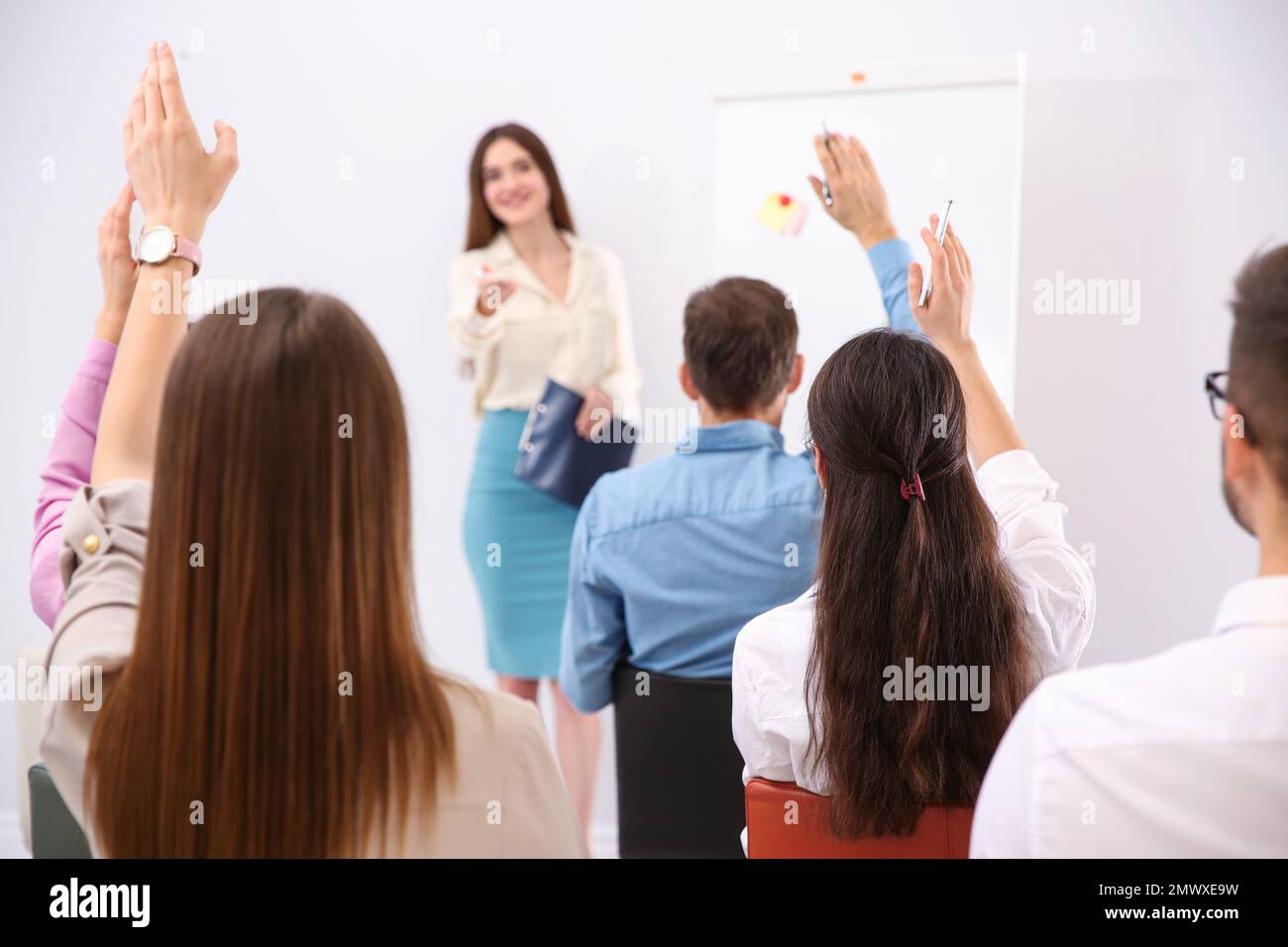 People raising hands to ask questions at business training indoors ...