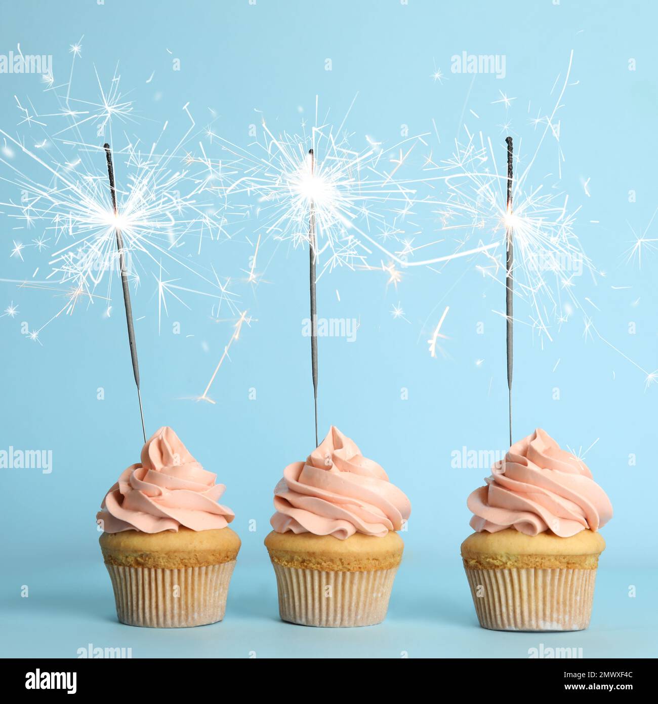 Birthday cupcakes with sparklers on light blue background Stock Photo - Alamy