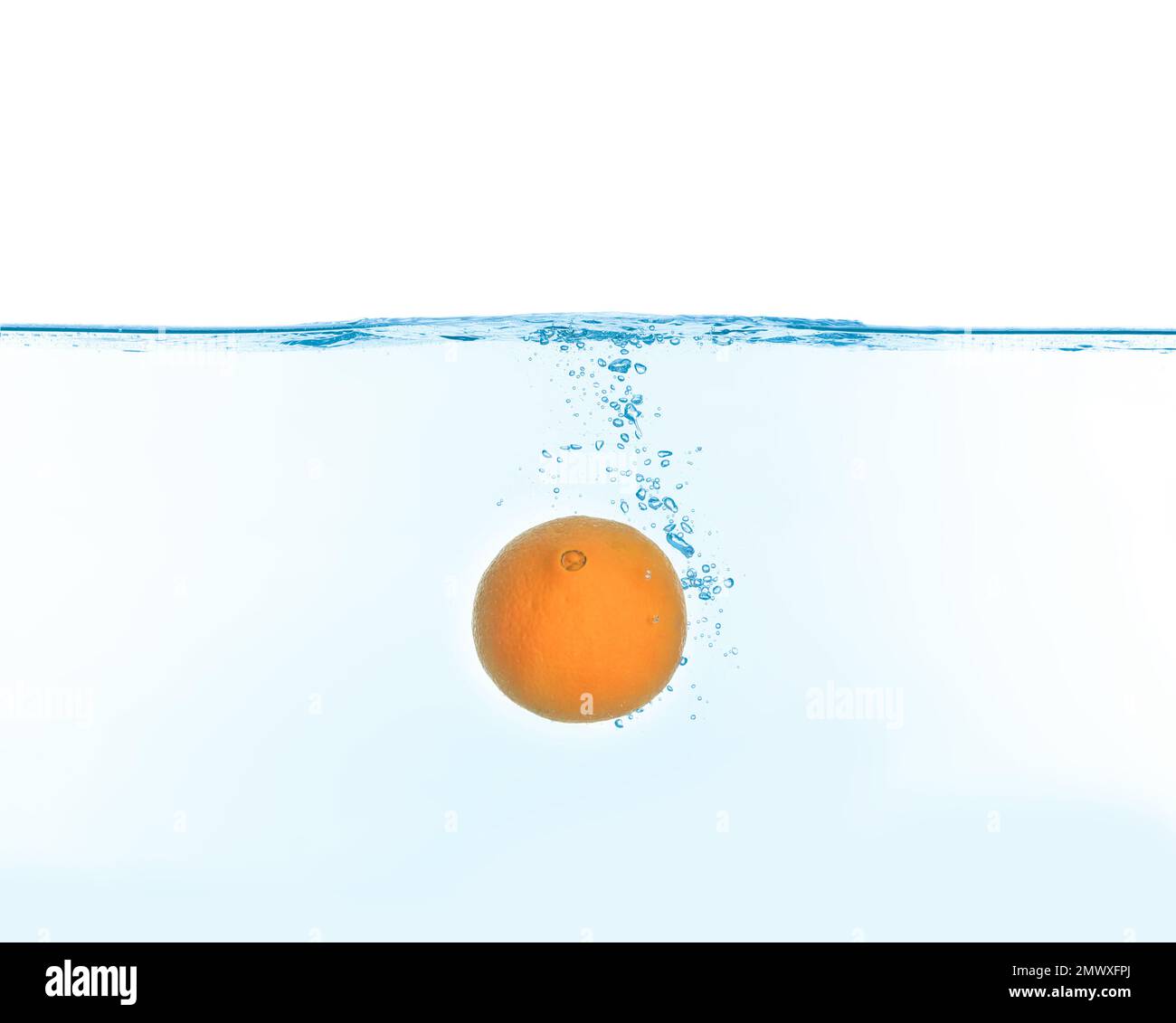 Ripe orange falling down into clear water against white background ...