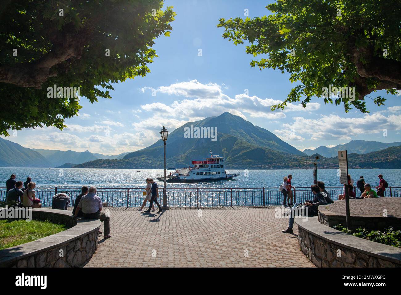 Tourists strolling along the lakefront of Varenna on a sunny day with ...