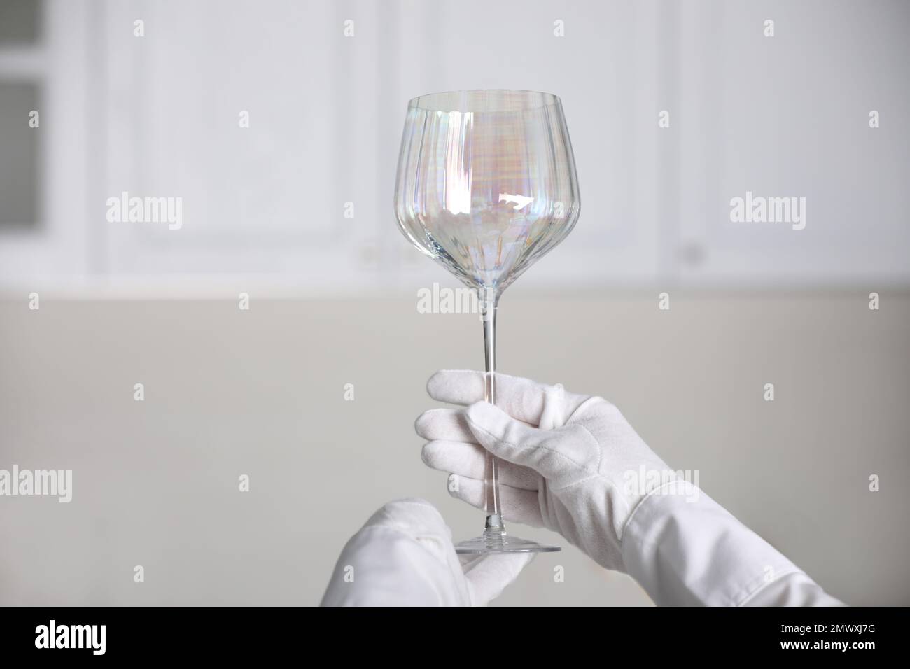 Person in white gloves checking cleanliness of glass indoors, closeup ...