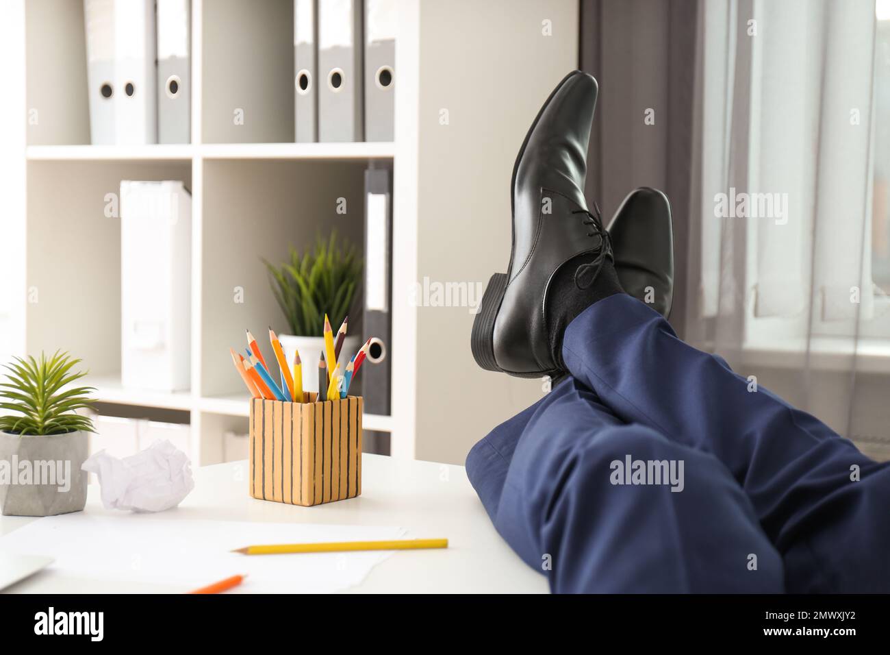 Lazy young man resting with feet on desk in office, closeup Stock Photo ...