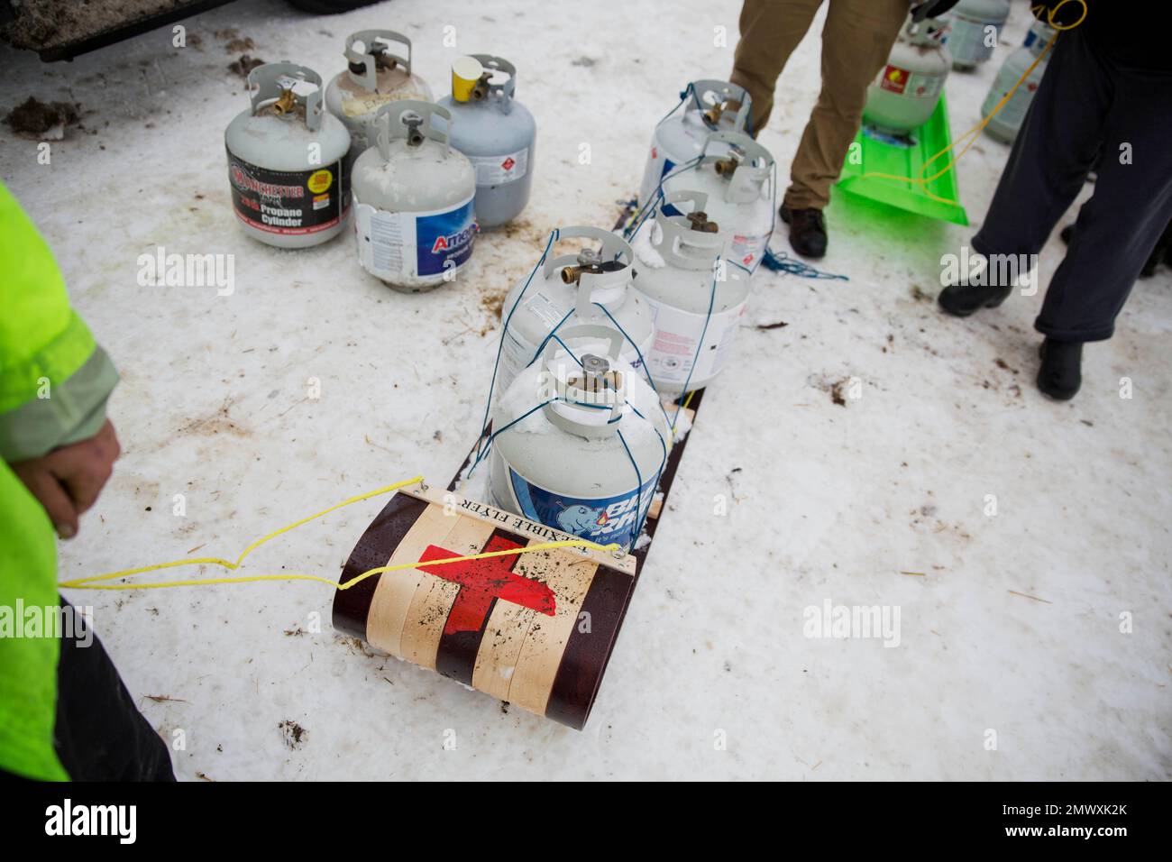 Propane tanks sits on a sled as people wait in line to have them filled ...