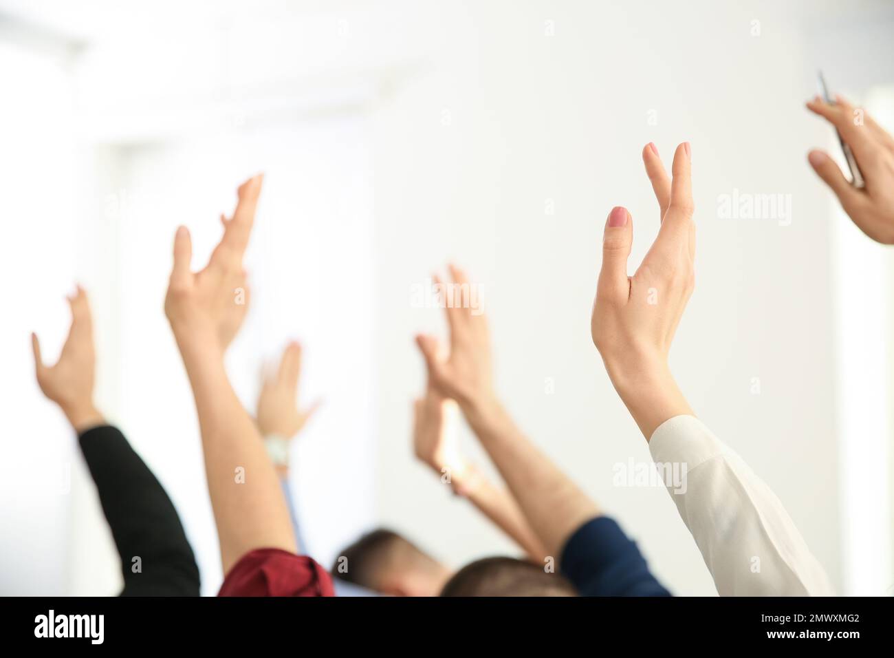People raising hands to ask questions at business training indoors ...
