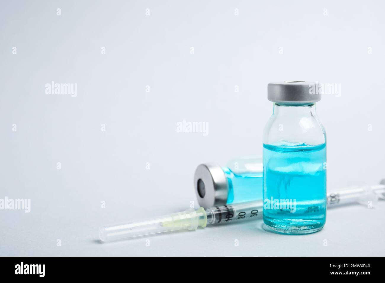 Vials and syringe on light background, space for text. Vaccination and ...