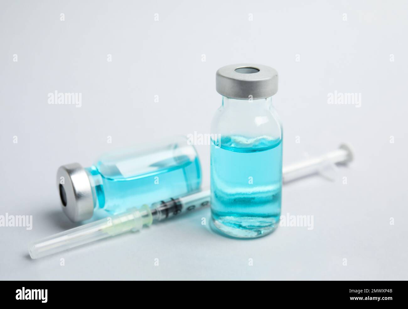 Vials and syringe on light background. Vaccination and immunization ...