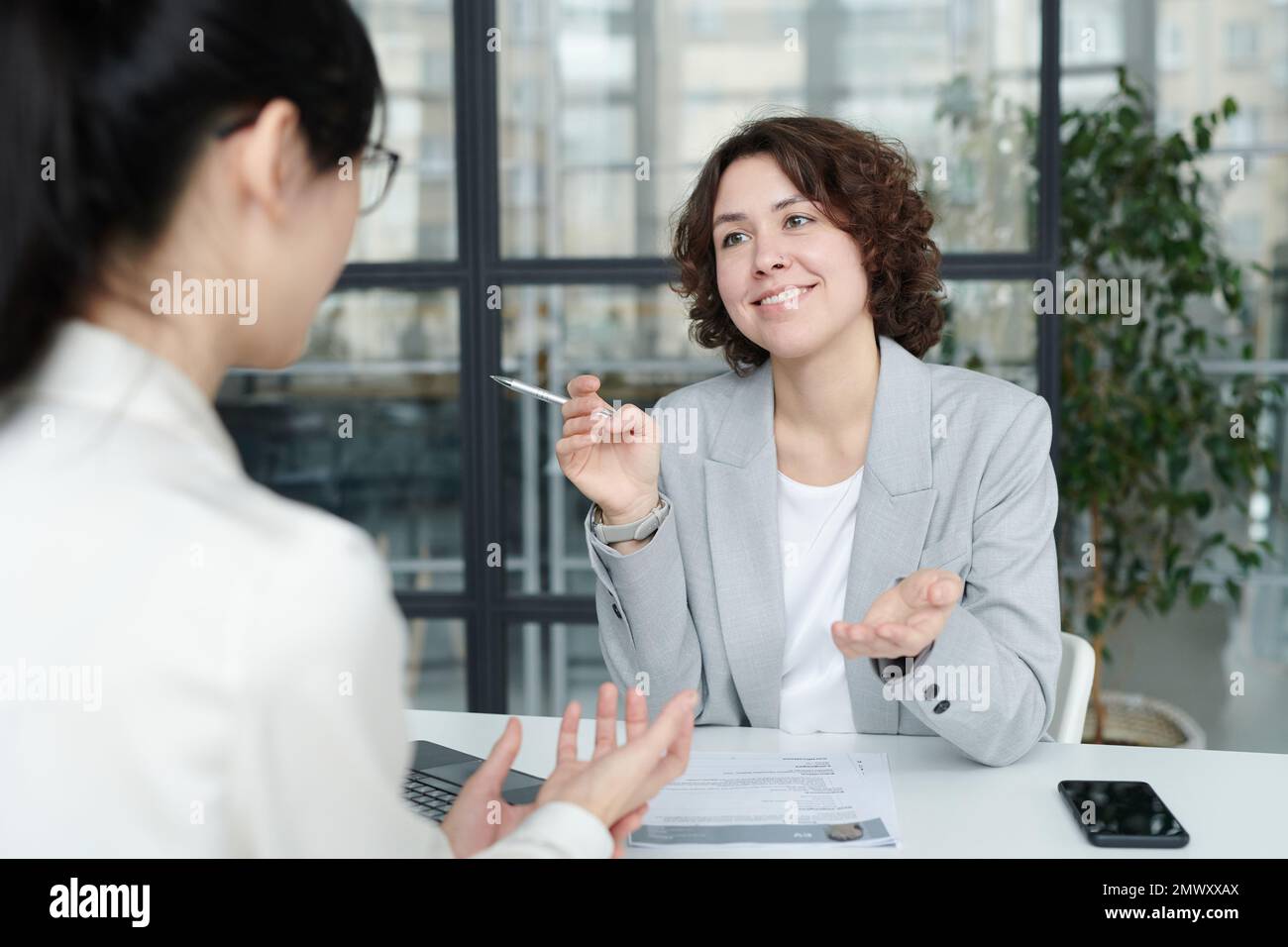Young interviewer discussing working moments with candidate during job ...