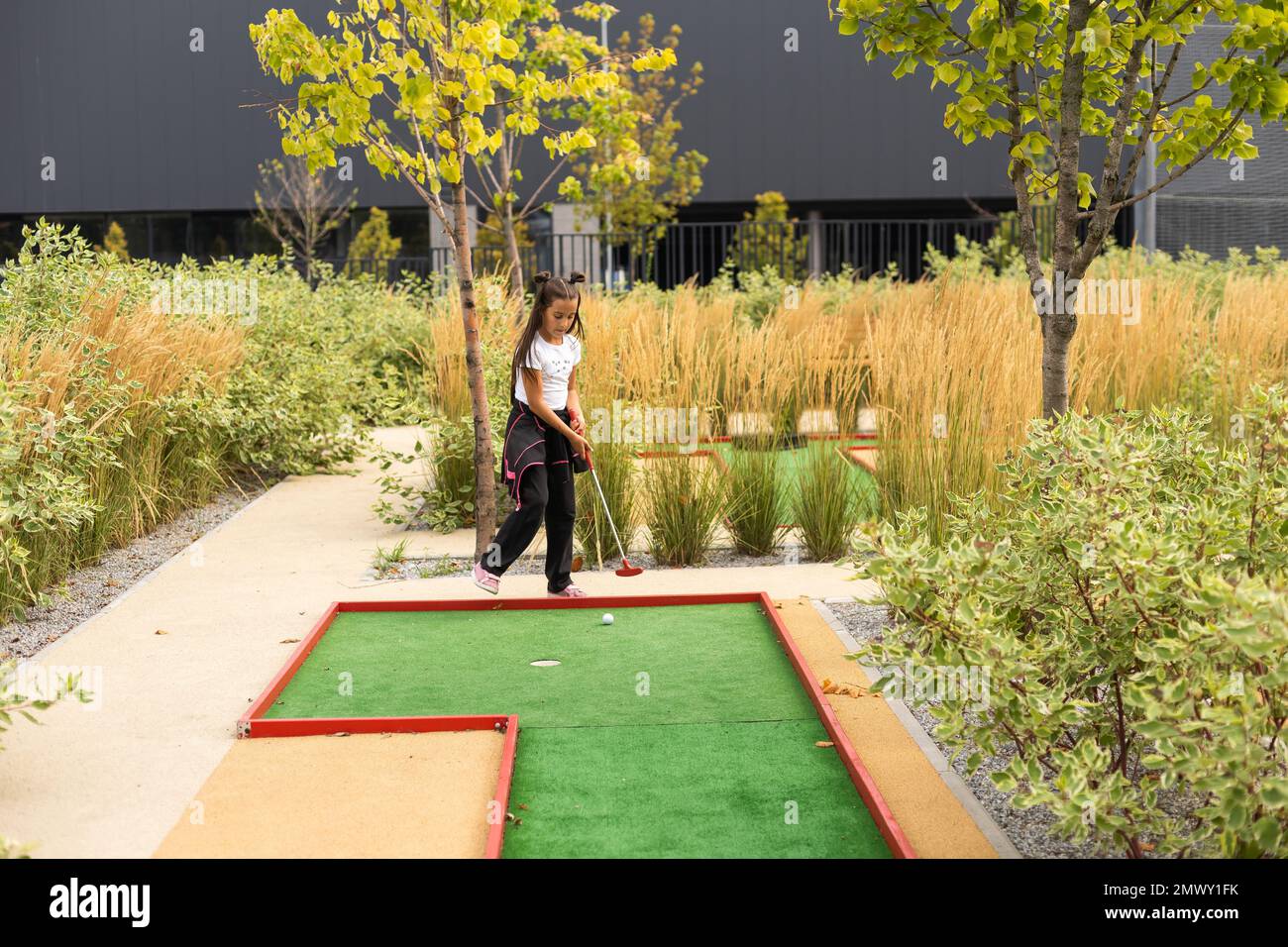 Cute preschool girl playing mini golf with family. Happy toddler child ...