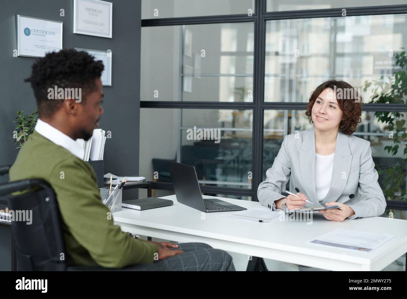 Young manager talking to candidate with disability during job interview ...