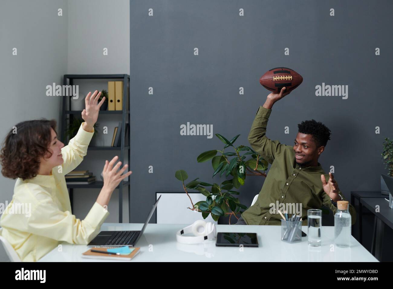 Two colleagues having fun during meeting at table, they playing rugby ...