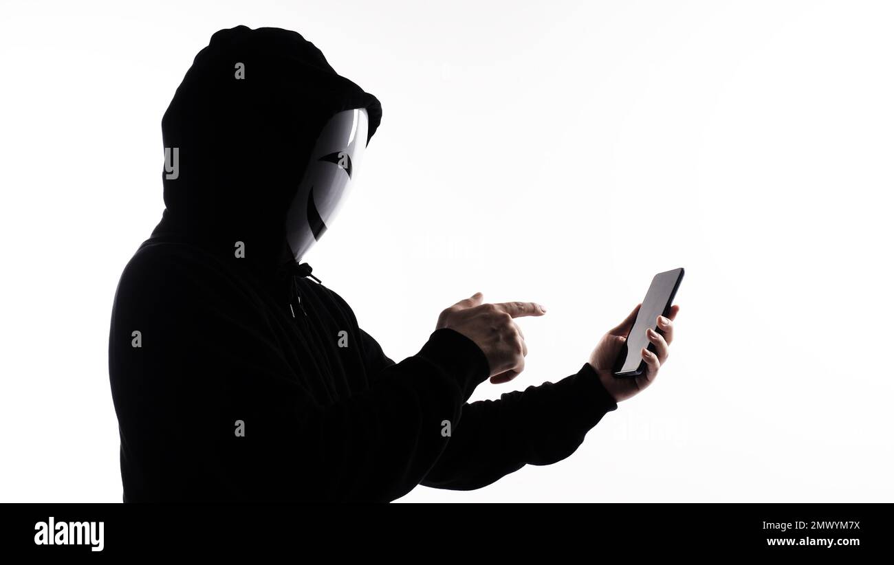 Hacker Anonymous and face mask with smartphone in hand. Man in black ...