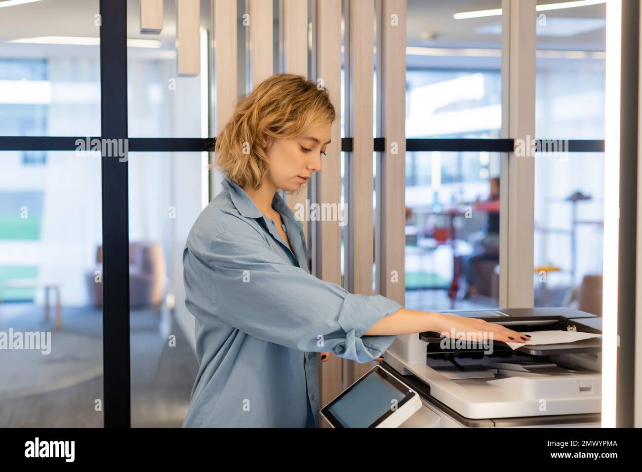 young blonde woman with wavy hair using modern printer in office,stock ...