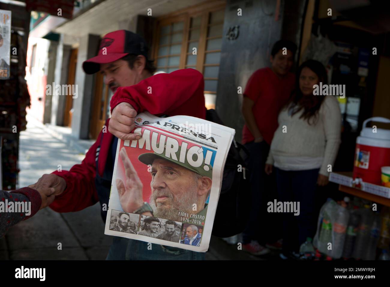 A man stops to buy a newspaper with a front page featuring images of ...