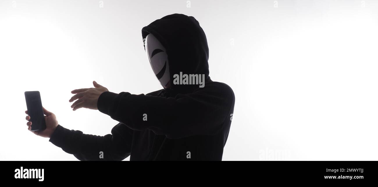 Hacker Anonymous and face mask with smartphone in hand. Man in black ...