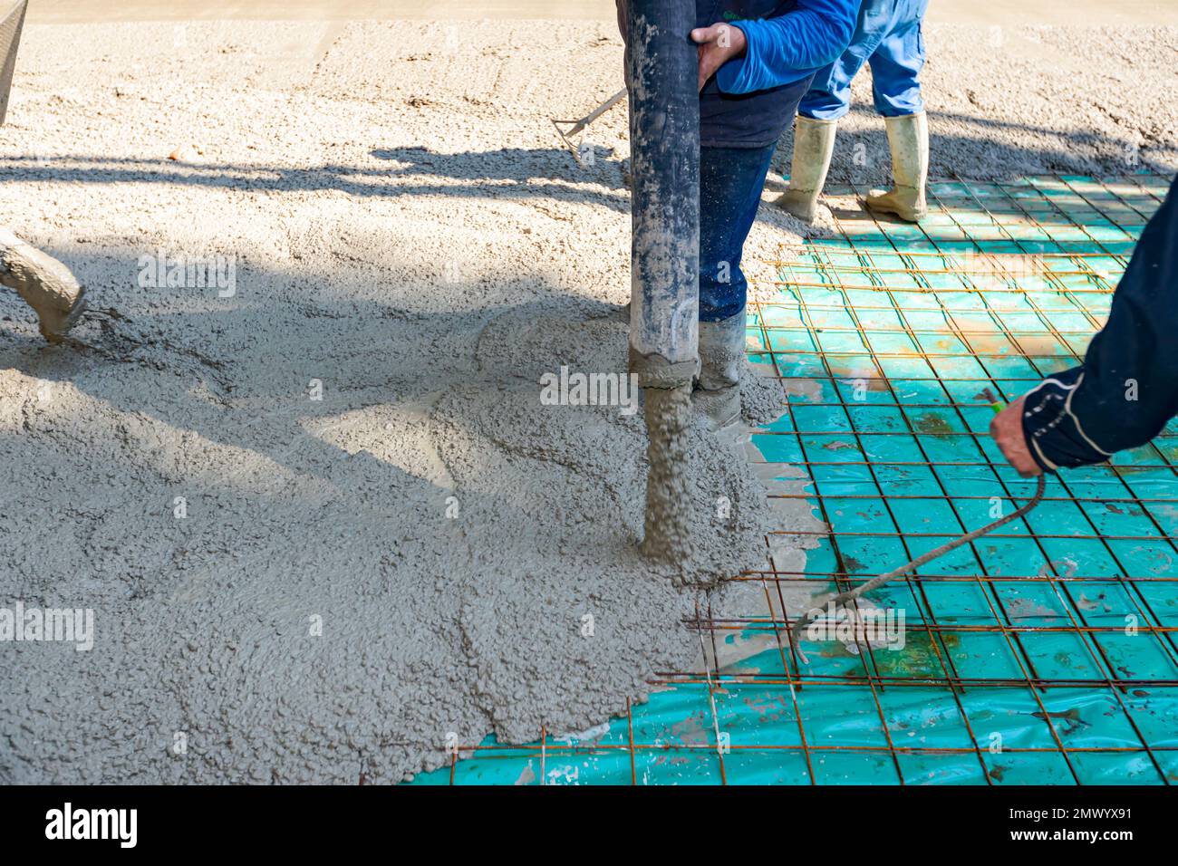 Construction worker is directing pump tube on direction, pouring layer ...
