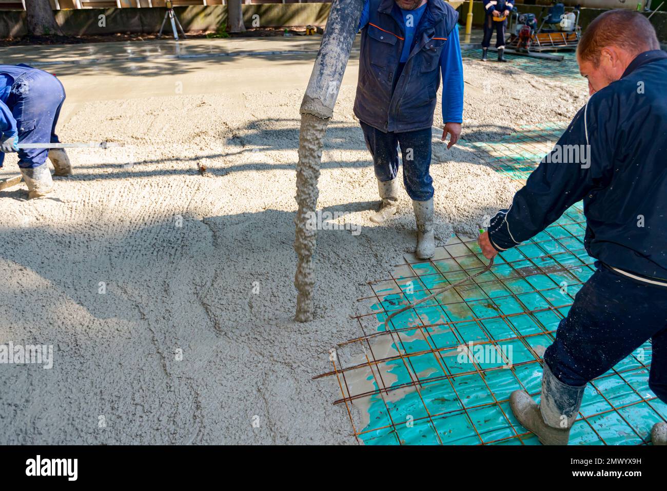 Construction worker is directing pump tube on direction, pouring layer ...