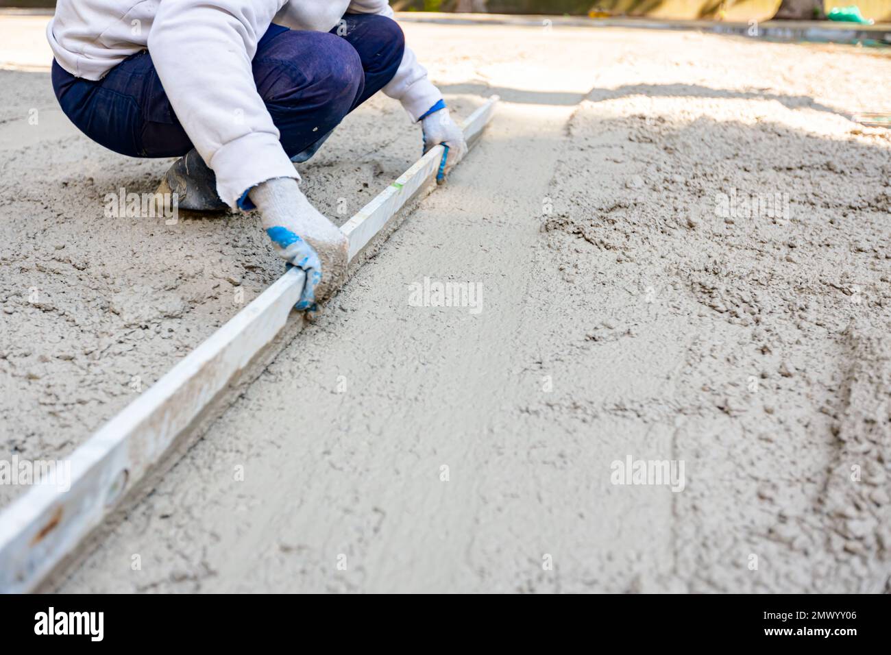 Construction worker is wearing gloves as leveling fresh concrete with ...