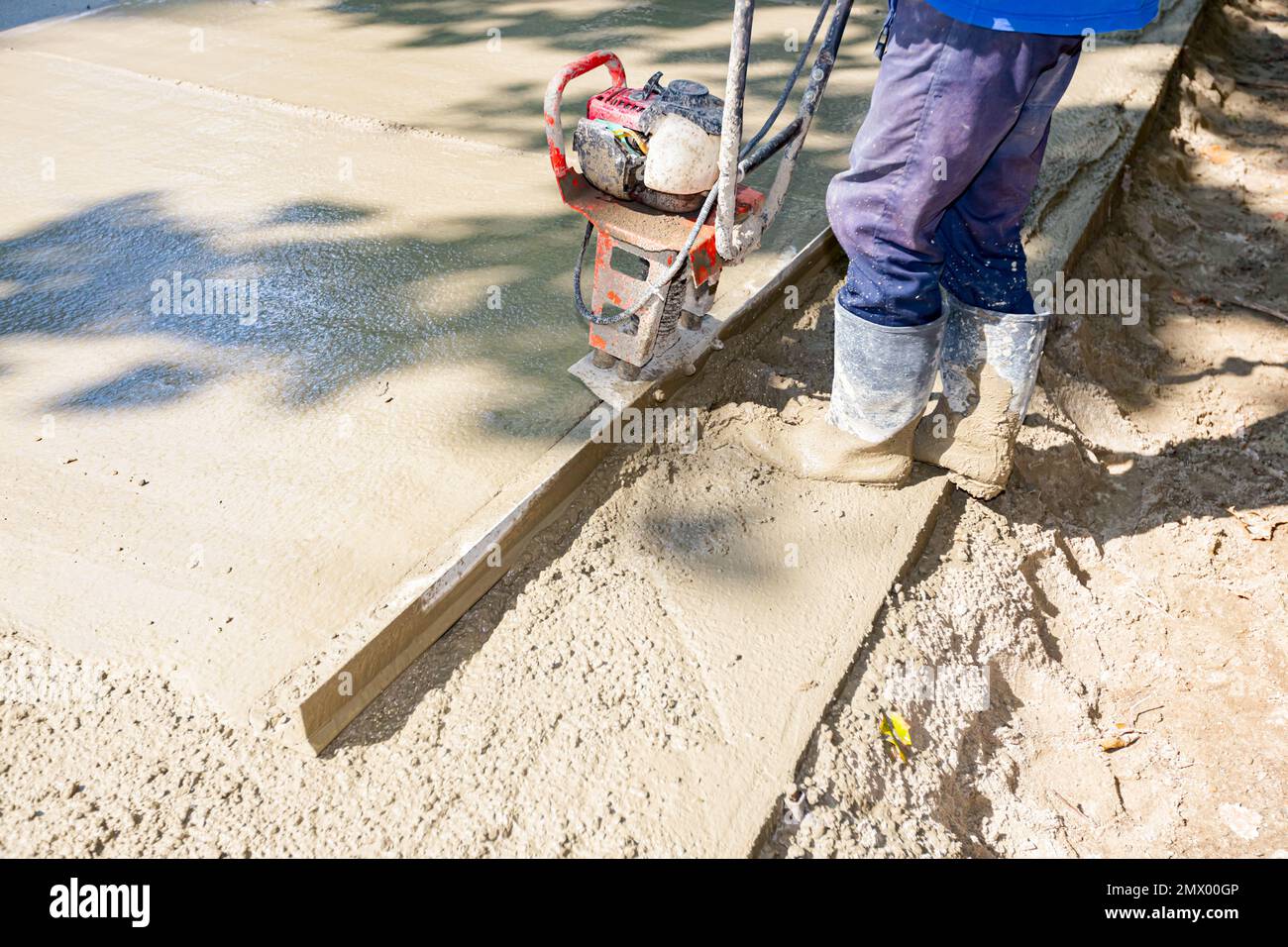 Construction worker is wearing gloves as leveling fresh concrete with ...