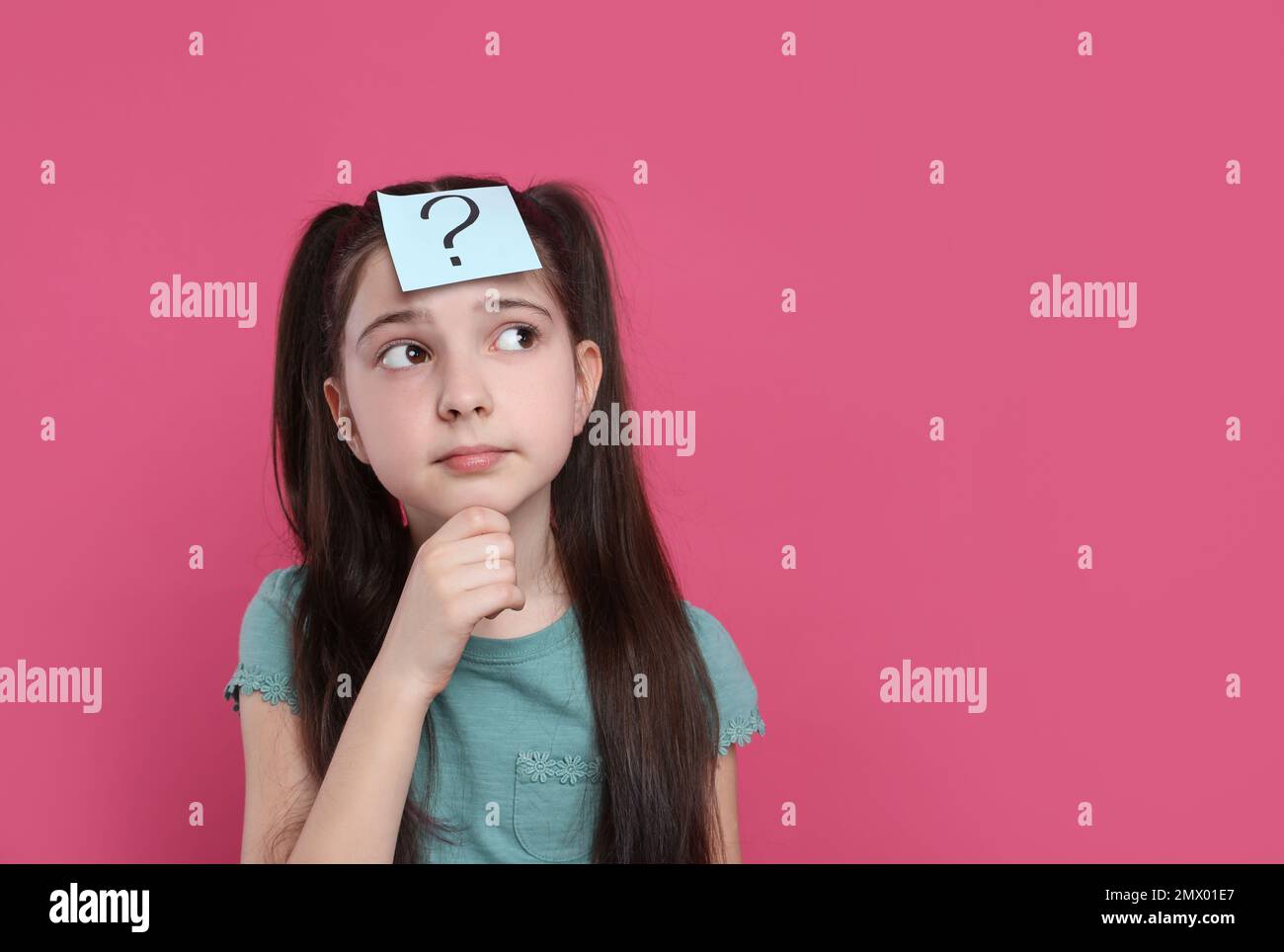 Pensive girl with question mark sticker on forehead against pink ...