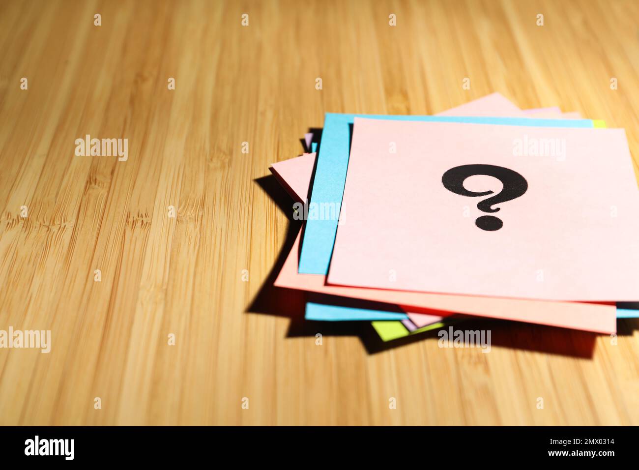 Paper cards with question mark on wooden background, closeup. Space for ...