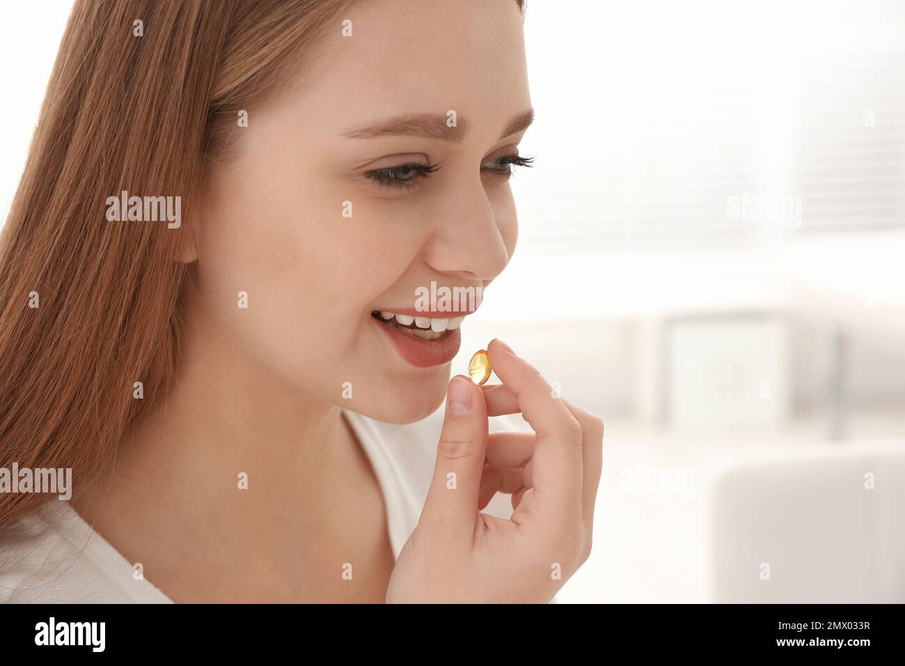 Young woman taking vitamin capsule on light background Stock Photo - Alamy