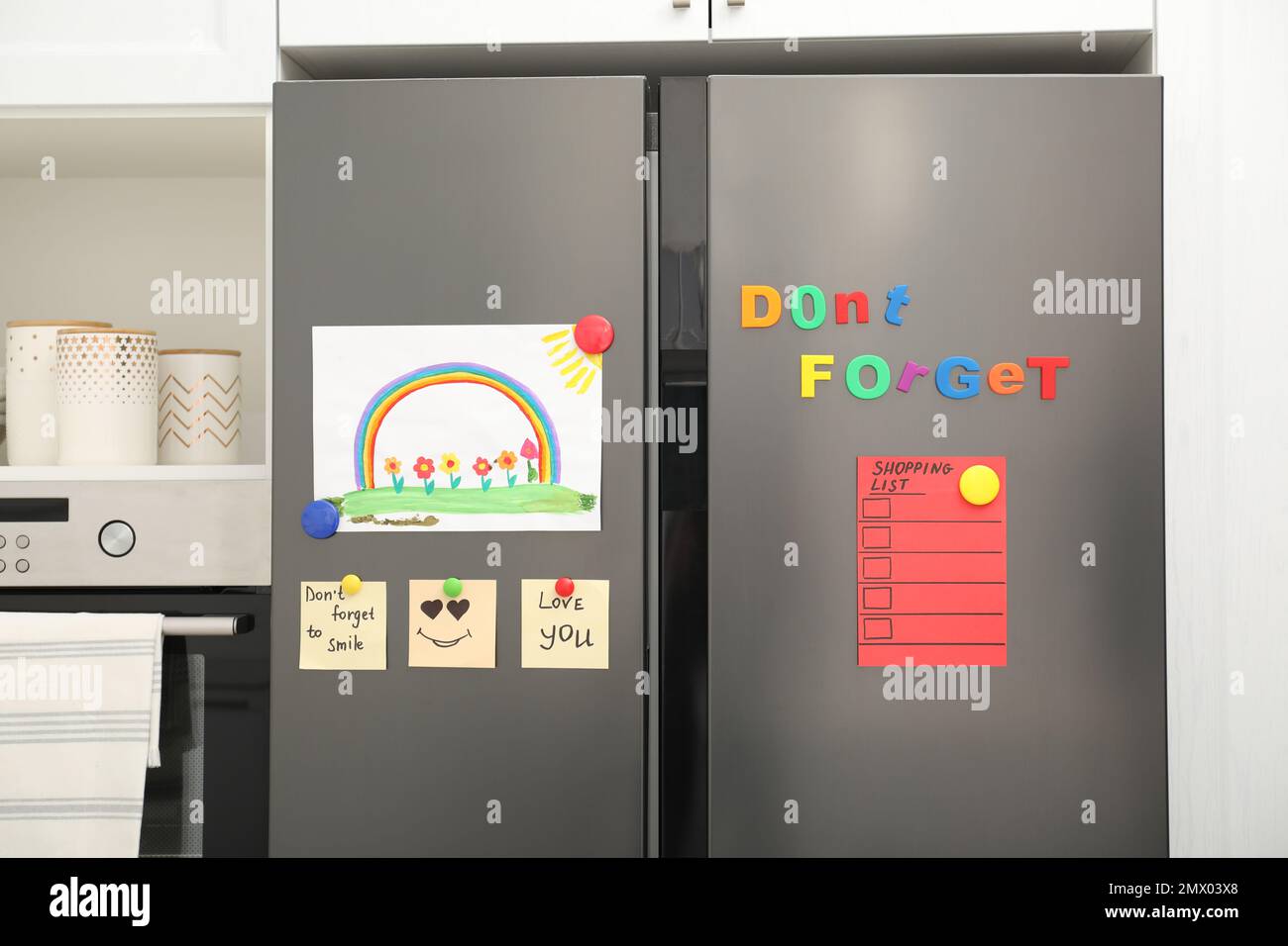 Modern refrigerator with child's drawing, notes and magnets in kitchen ...
