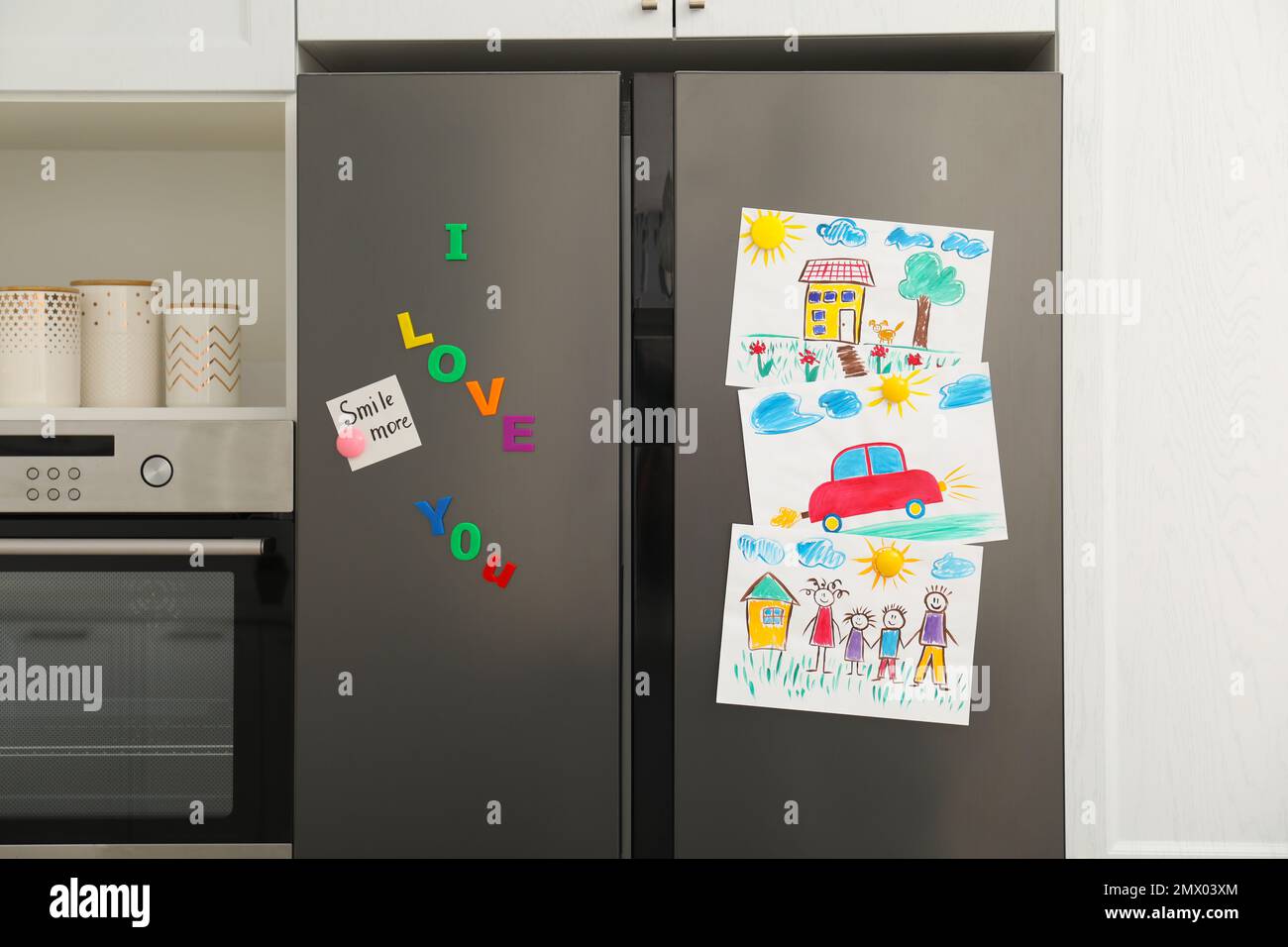 Modern refrigerator with child's drawings, note and magnets in kitchen ...