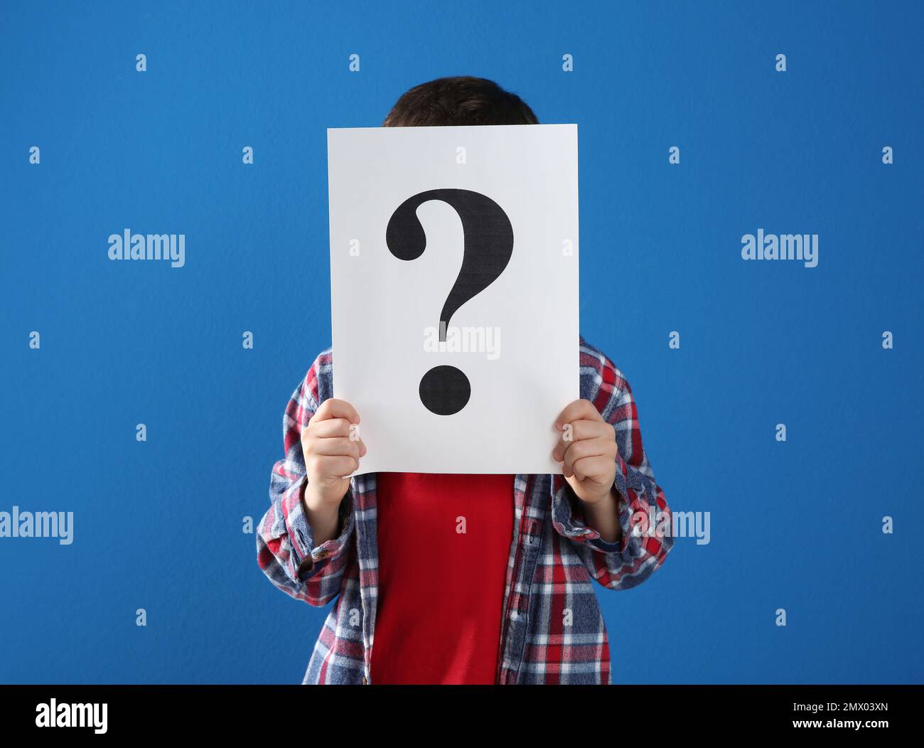 Little boy holding paper with question mark on blue background Stock ...