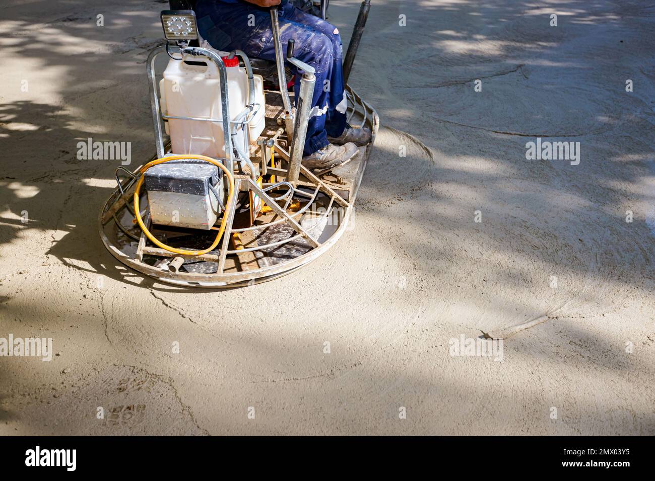 Worker sitting on a self-leveling power trowel machine with gas engine ...