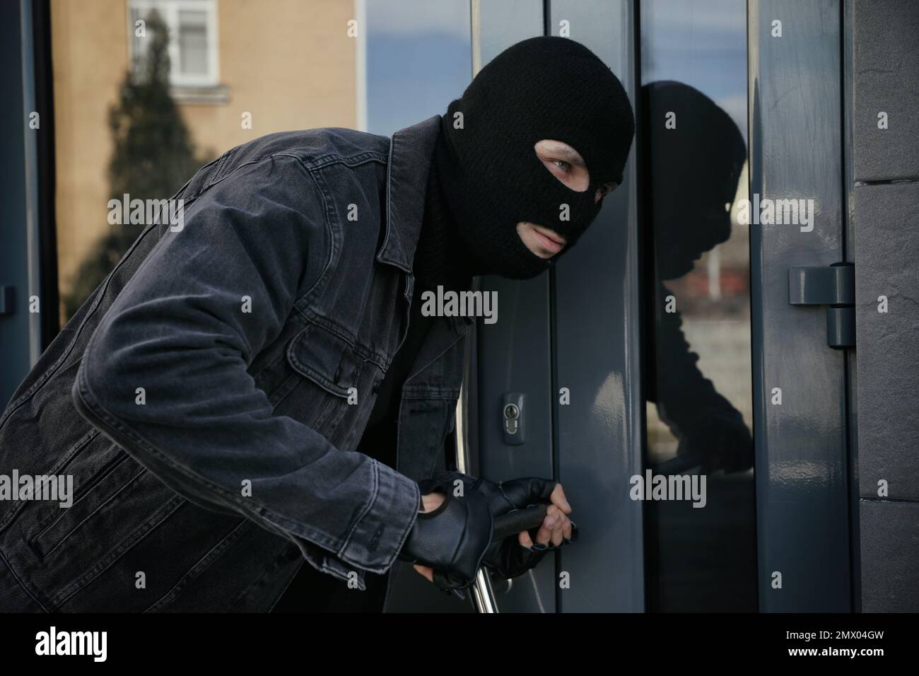 Man in mask forcing door with crow bar. Dangerous criminal Stock Photo ...
