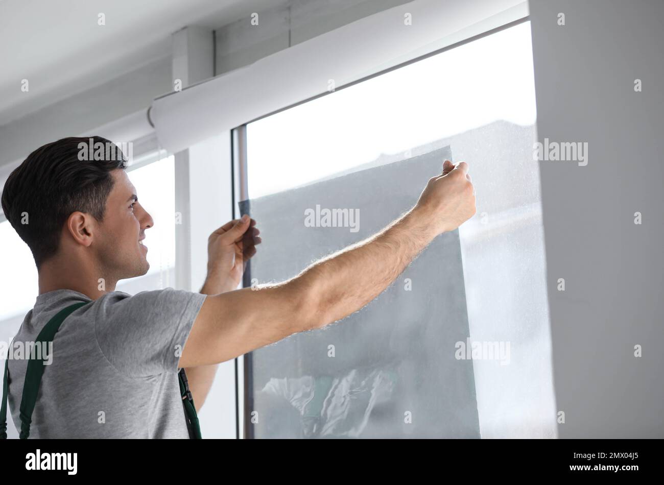Professional worker tinting window with foil indoors Stock Photo - Alamy