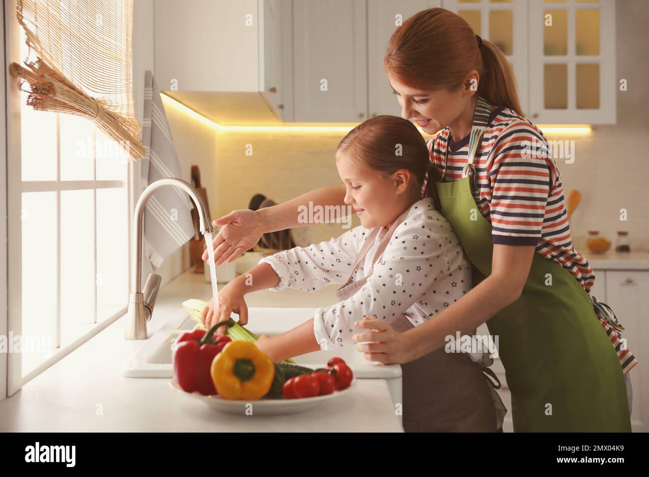 Mother and daughter washing vegetables in kitchen Stock Photo - Alamy