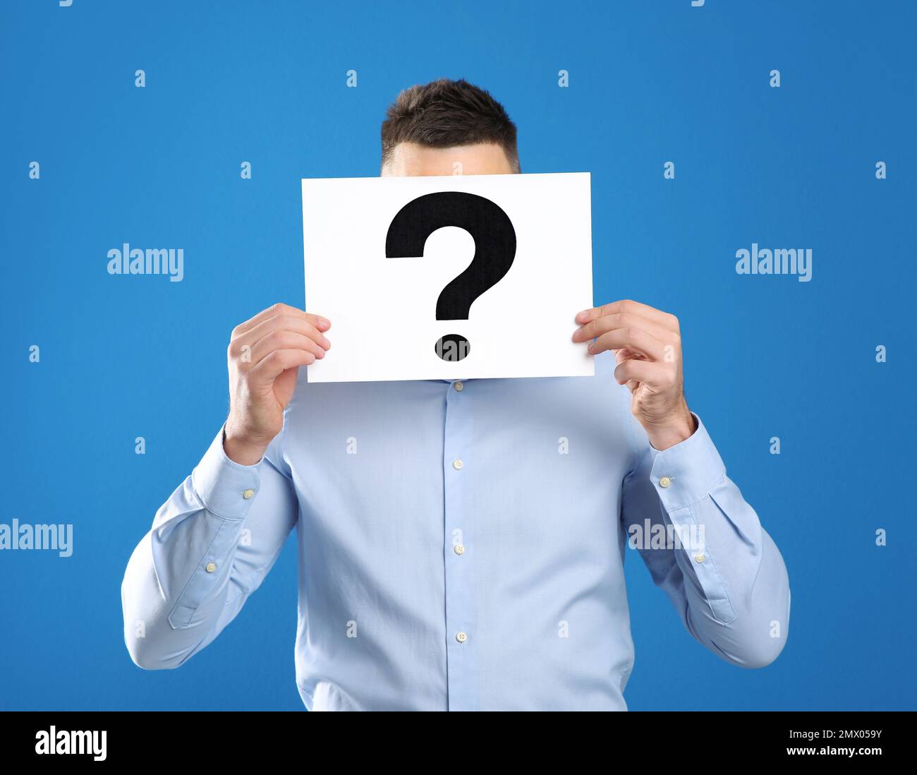 Man holding paper with question mark on blue background Stock Photo - Alamy