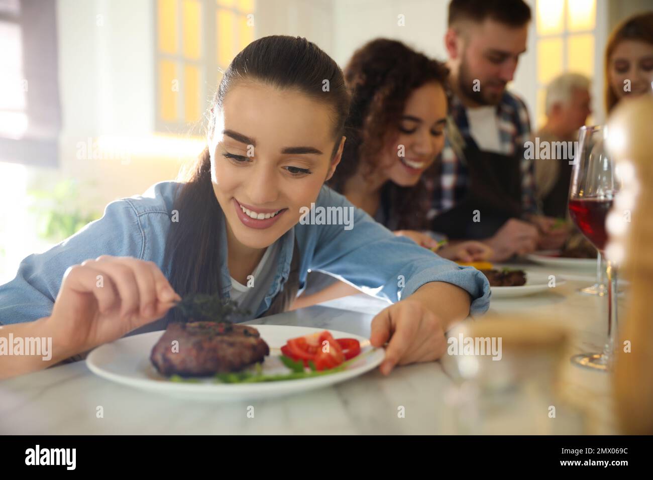 Young woman serving food in crowded kitchen. Cooking class Stock Photo ...