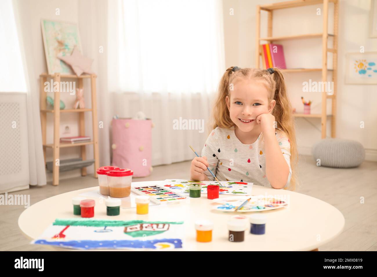 Cute little child painting at table in room Stock Photo - Alamy
