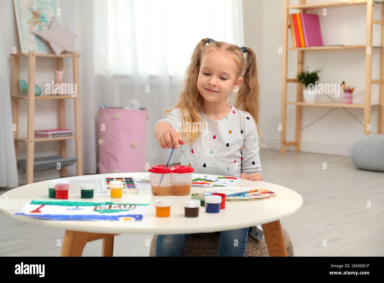 Cute little child painting at table in room Stock Photo - Alamy