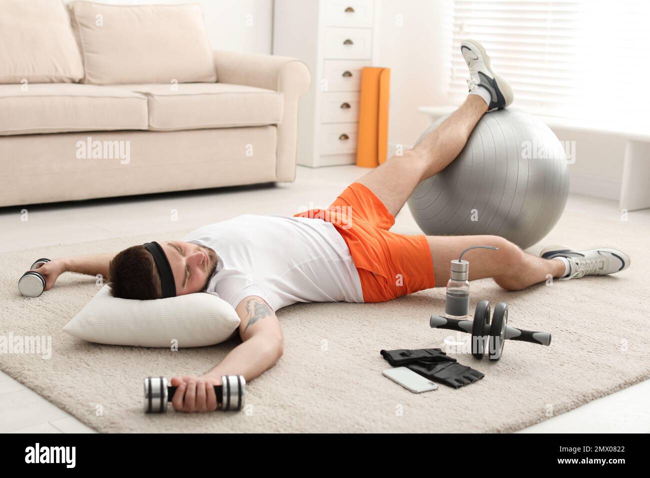 Lazy young man with sport equipment sleeping on floor at home Stock ...
