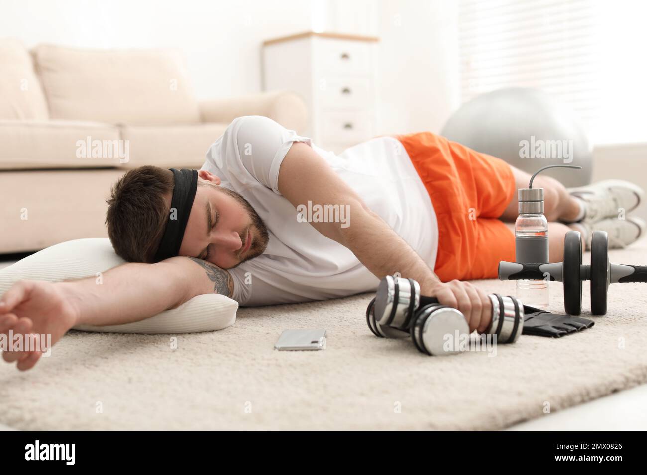 Lazy young man with sport equipment sleeping on floor at home Stock ...
