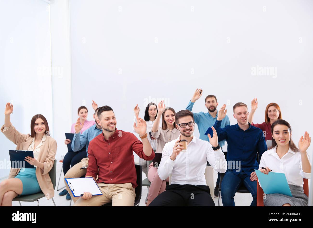 People raising hands to ask questions at business training indoors ...