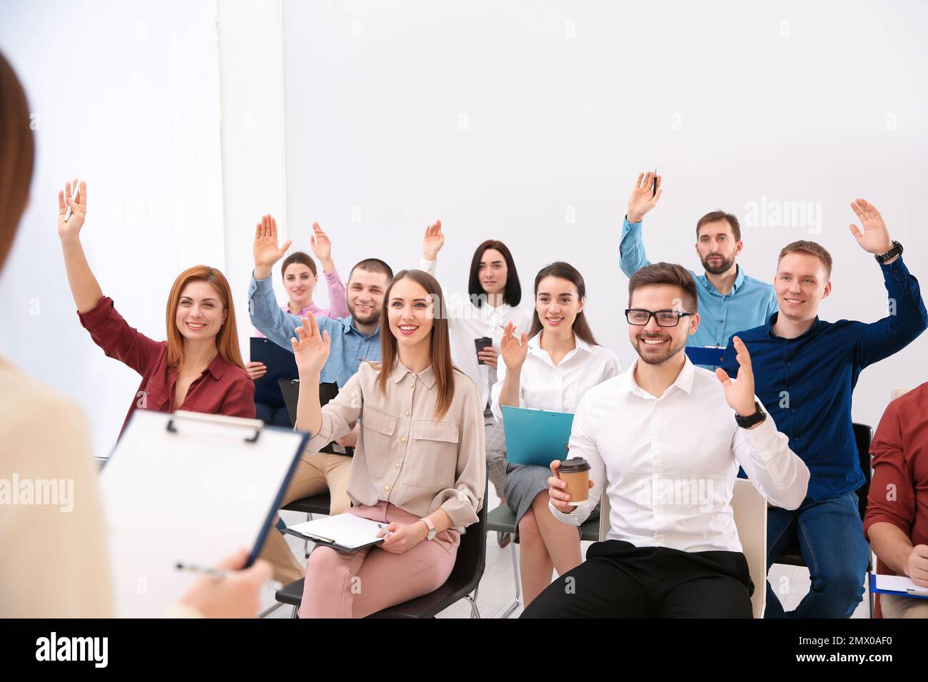 People raising hands to ask questions at business training indoors ...