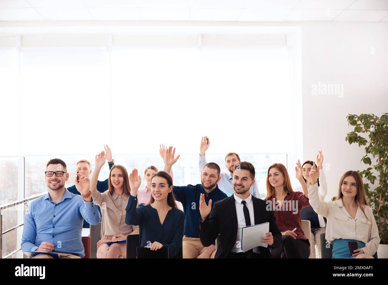 People raising hands to ask questions at business training indoors ...