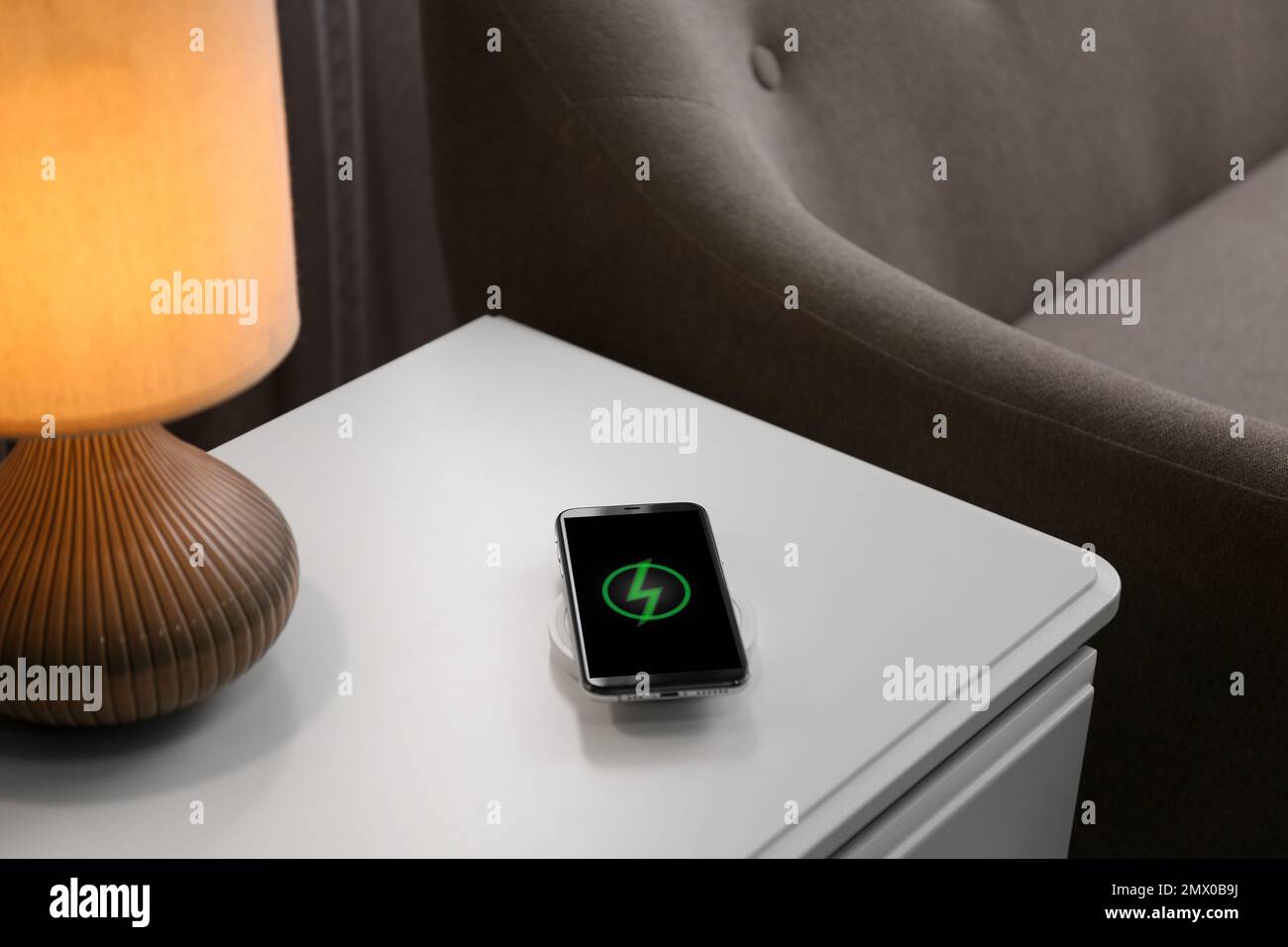 Smartphone charging on wireless pad in room Stock Photo - Alamy