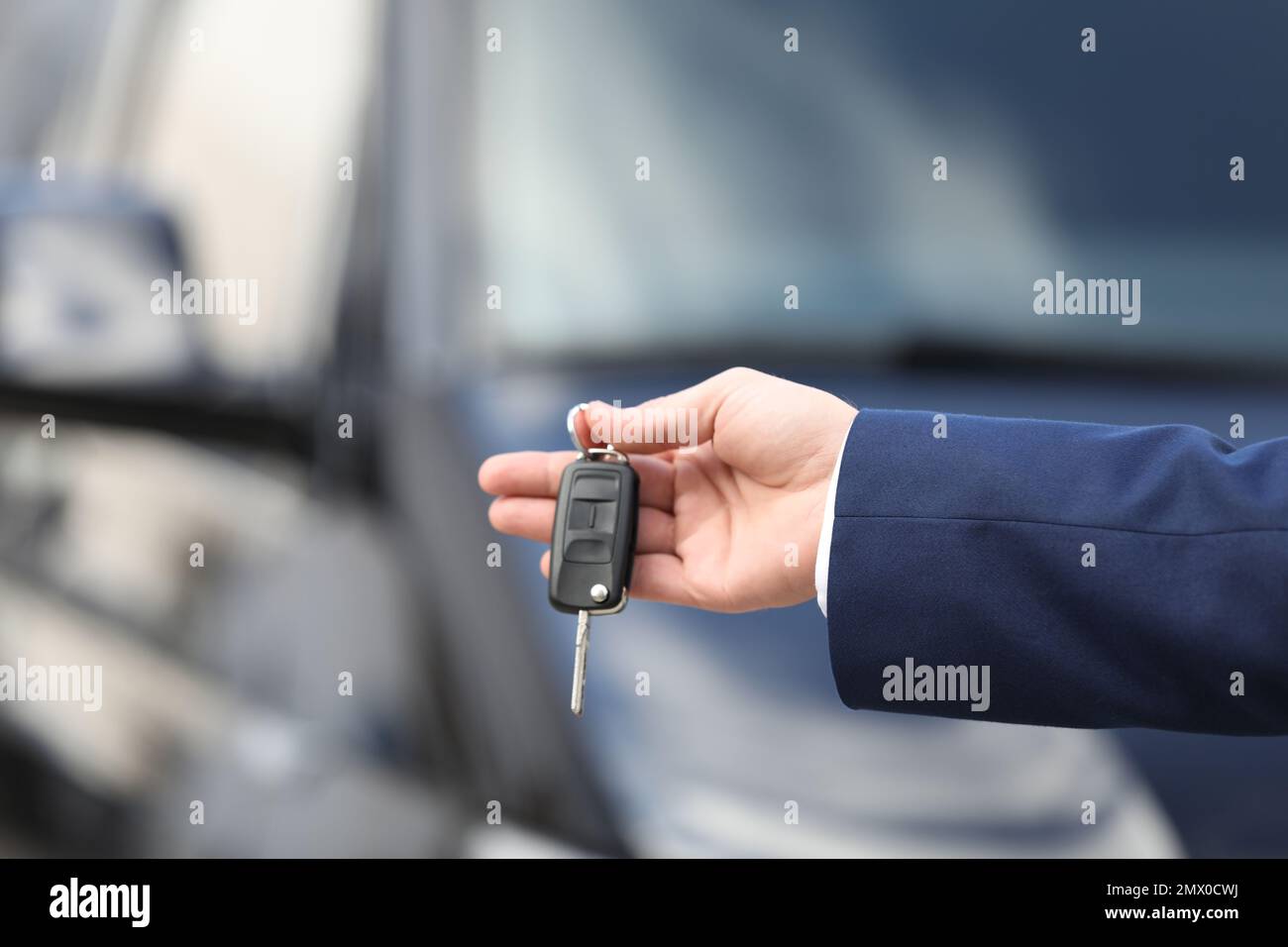 Man holding key in modern auto dealership, closeup. Buying new car ...