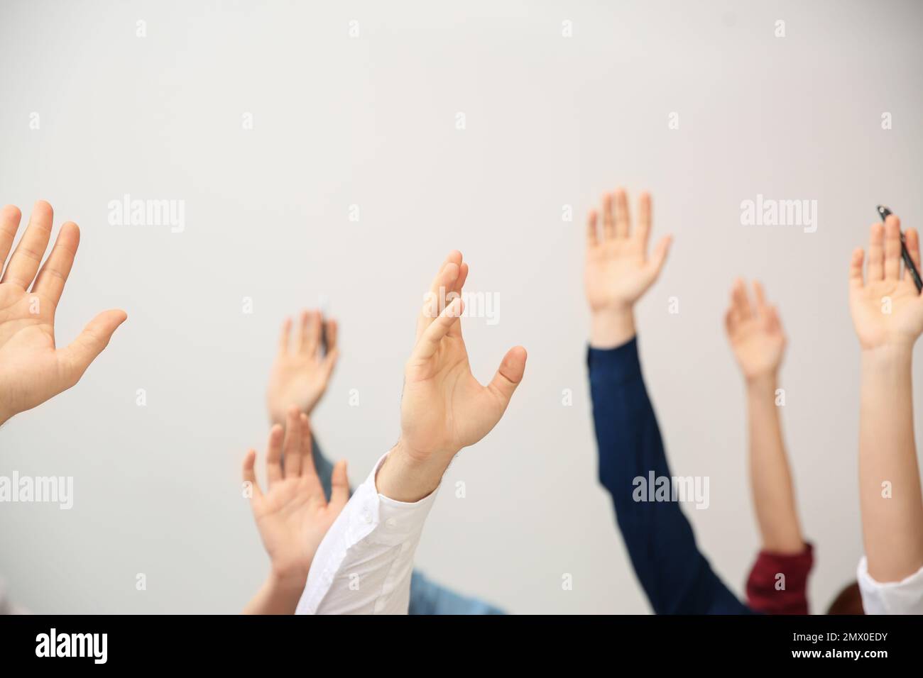 People raising hands to ask questions at business training on white ...